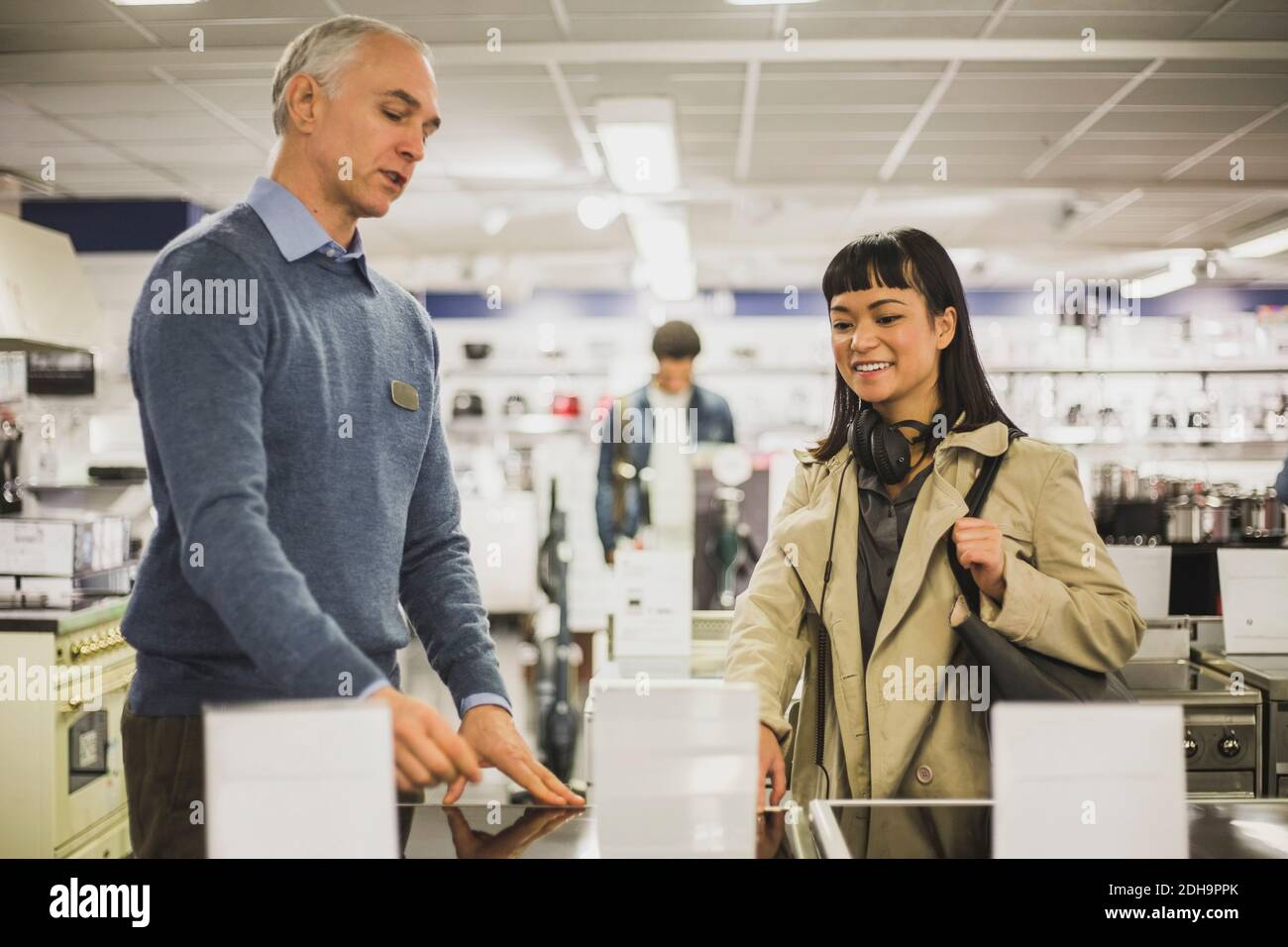 Mature owner talking to smiling female customer in electronics store ...