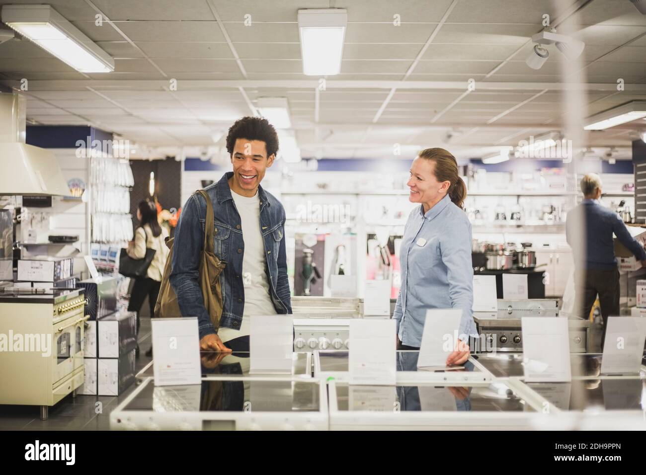 Smiling mature owner talking to male customer in electronics store ...