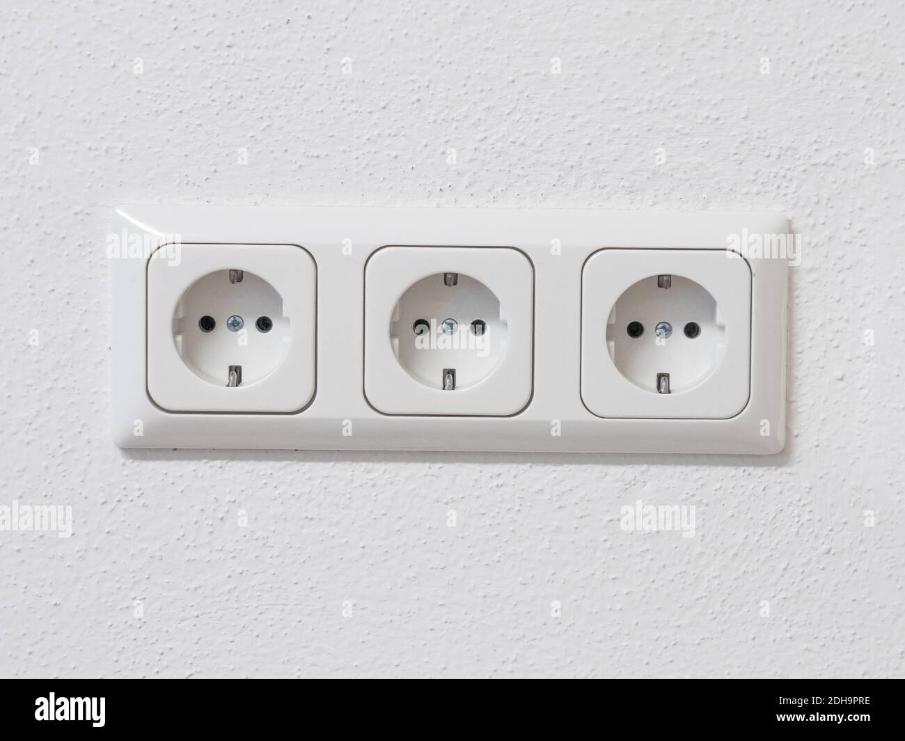 Triple white electrical wall socket in a textured white wall Stock ...