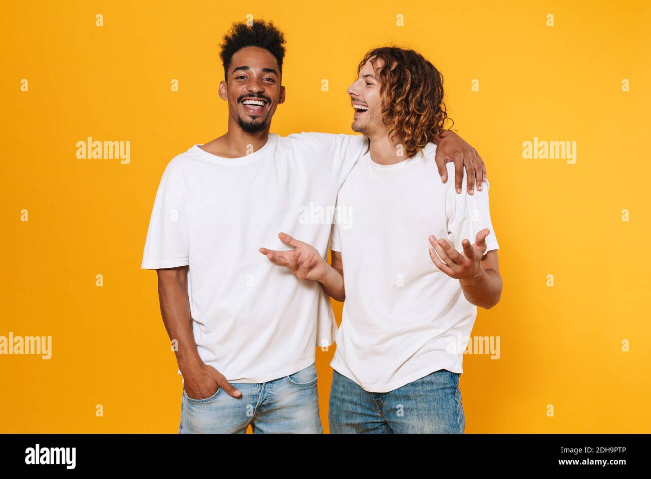 Cheerful multicultural two guys talking and hugging isolated over ...