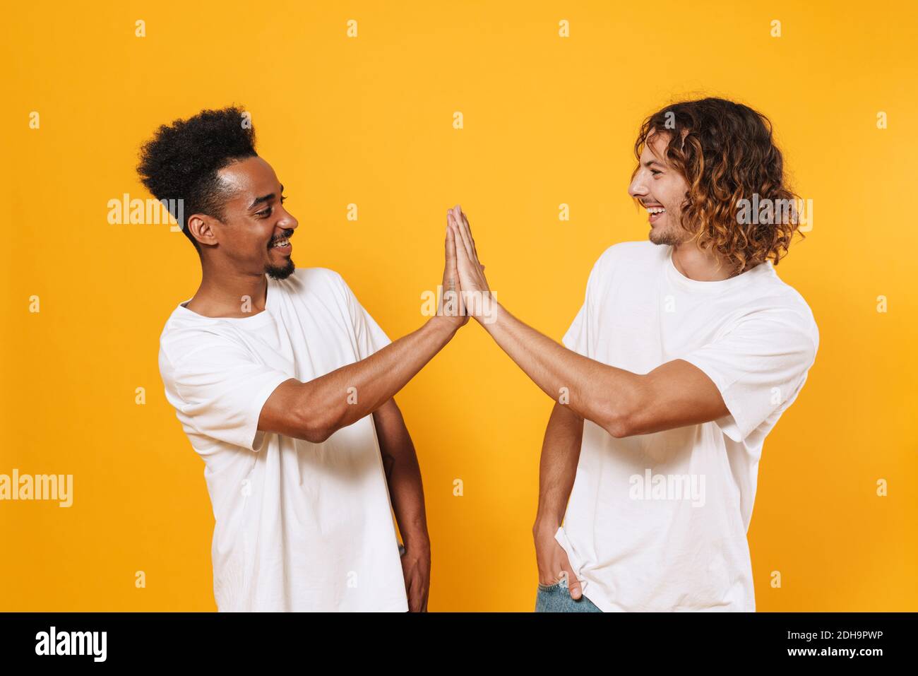 Happy multicultural two guys smiling and giving high five isolated over ...