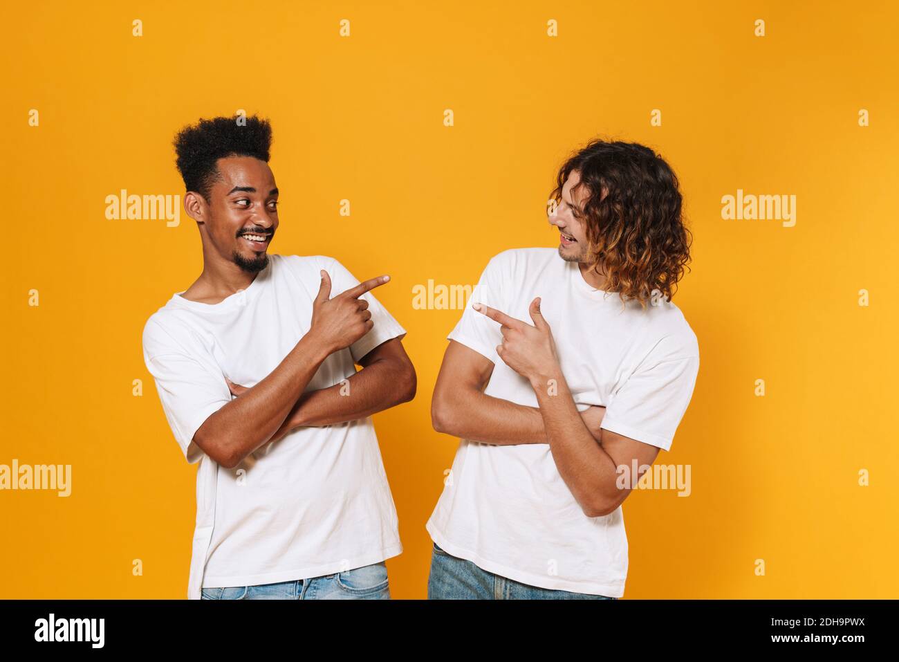 Happy multicultural two guys smiling and pointing fingers at each other ...