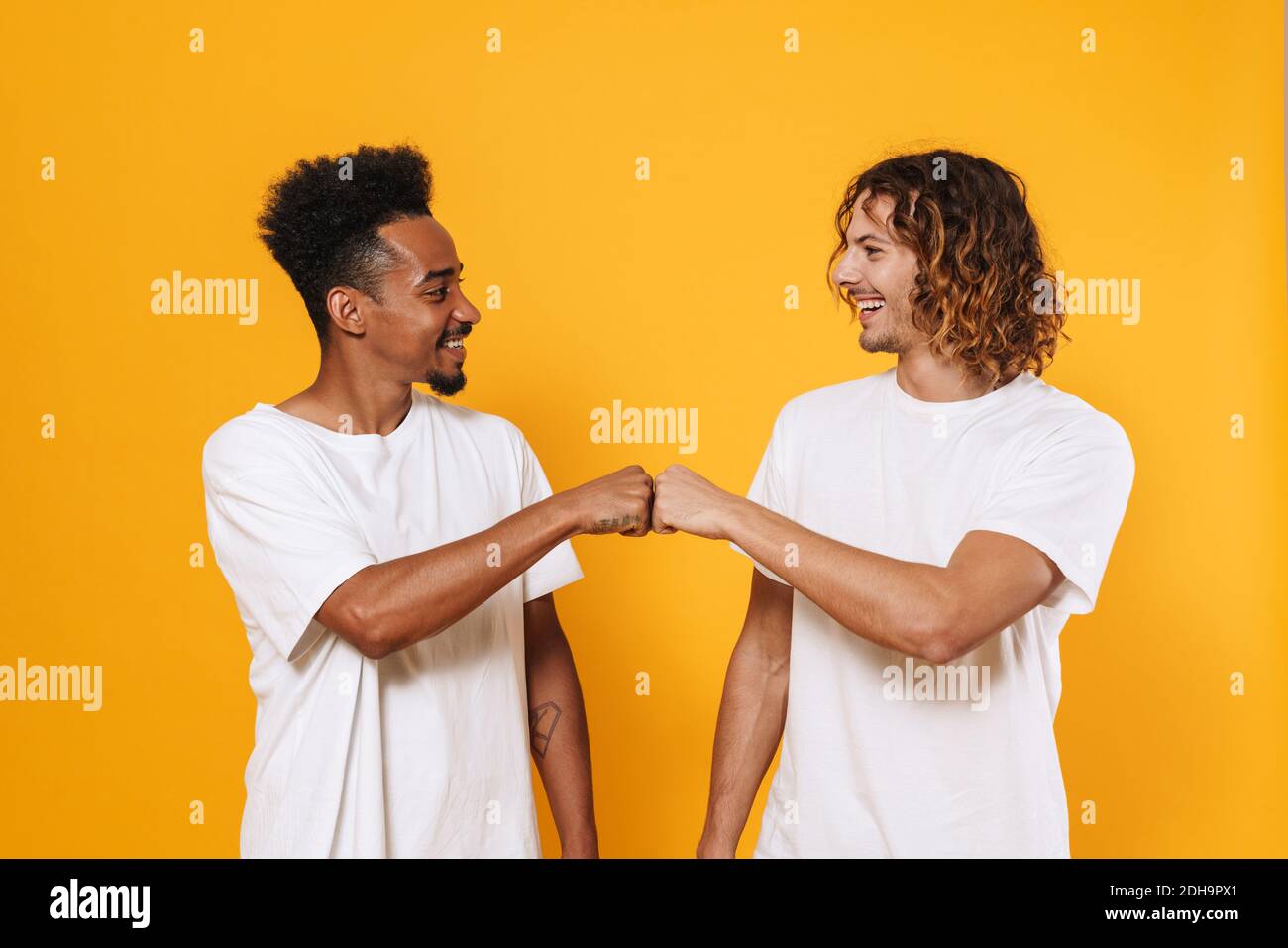 Happy multicultural two guys smiling and fist bumping isolated over ...