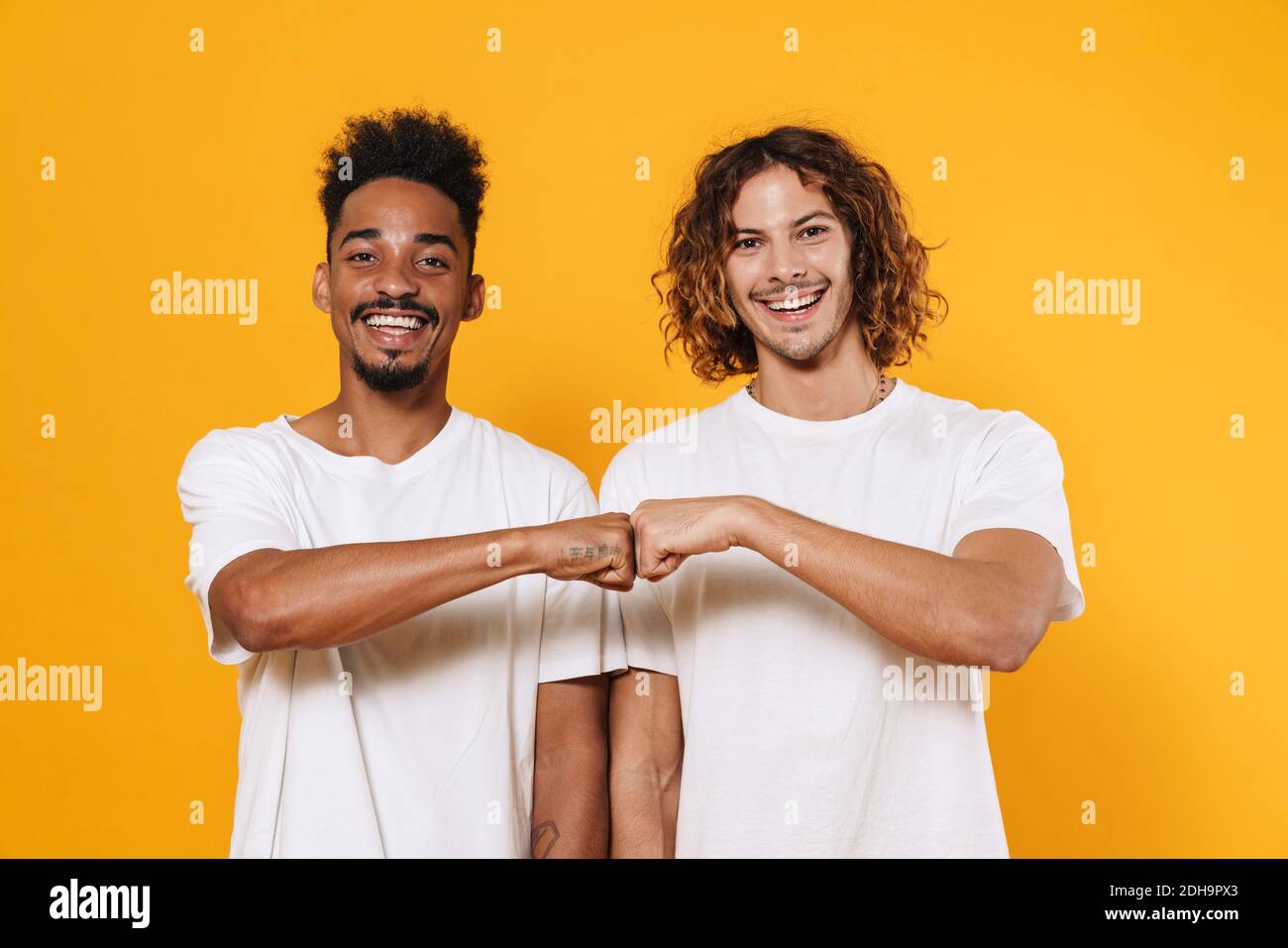 Happy multicultural two guys smiling and fist bumping isolated over ...