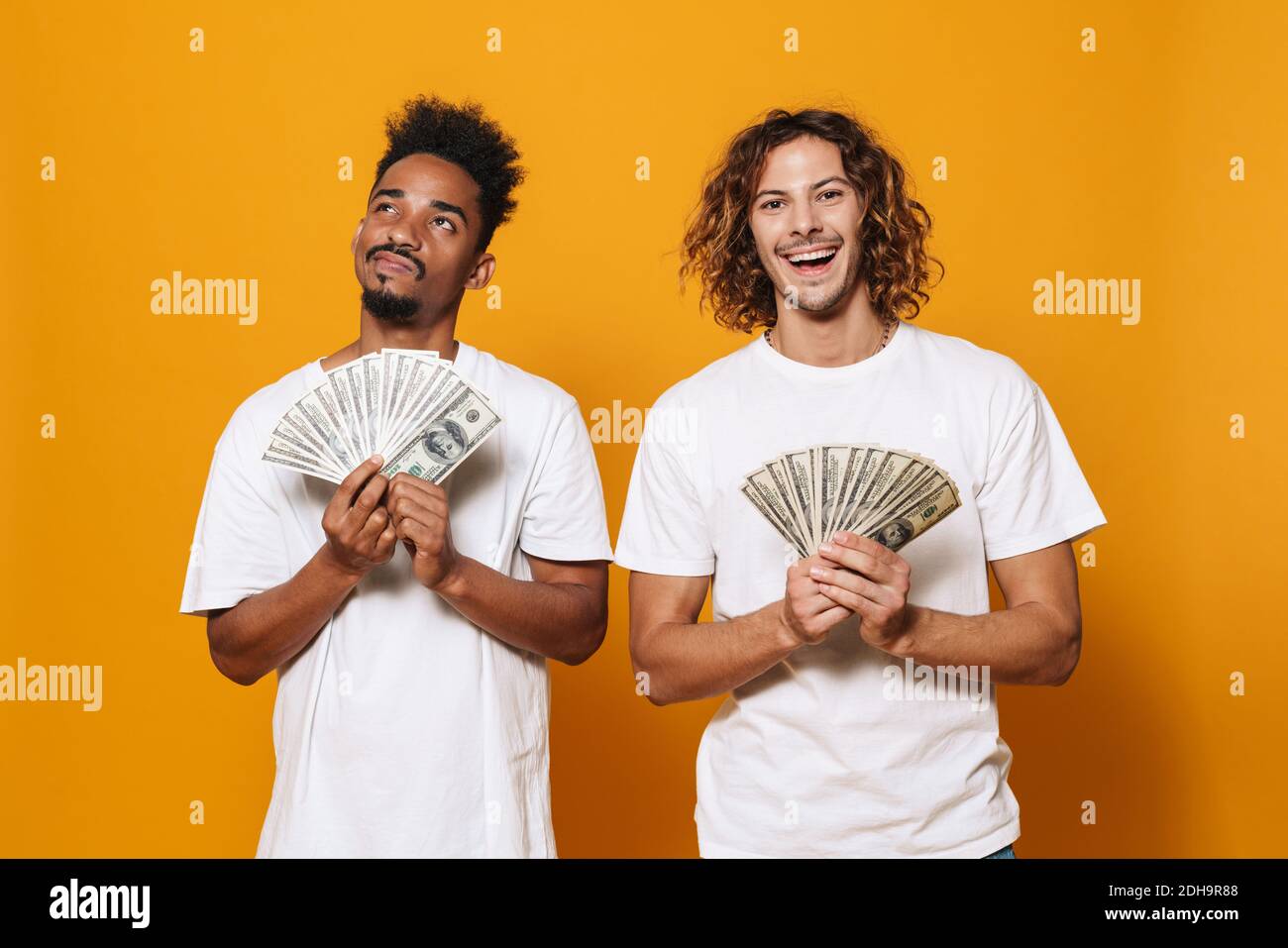 Handsome multicultural two guys posing with dollars isolated over ...