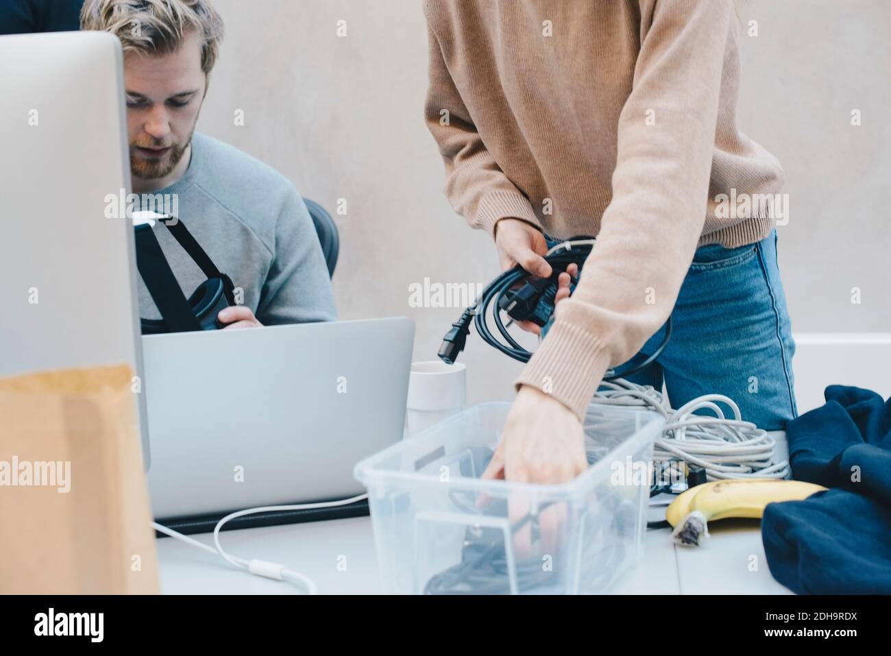 Midsection of female computer programmer removing cables from container ...