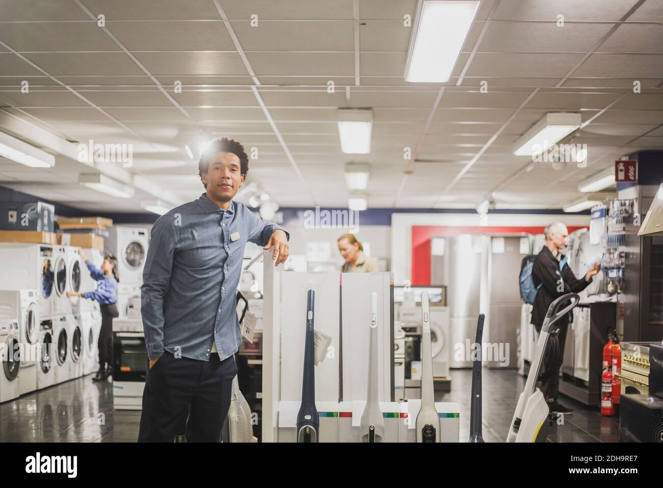 Portrait of male owner with hand in pocket standing in electronics ...