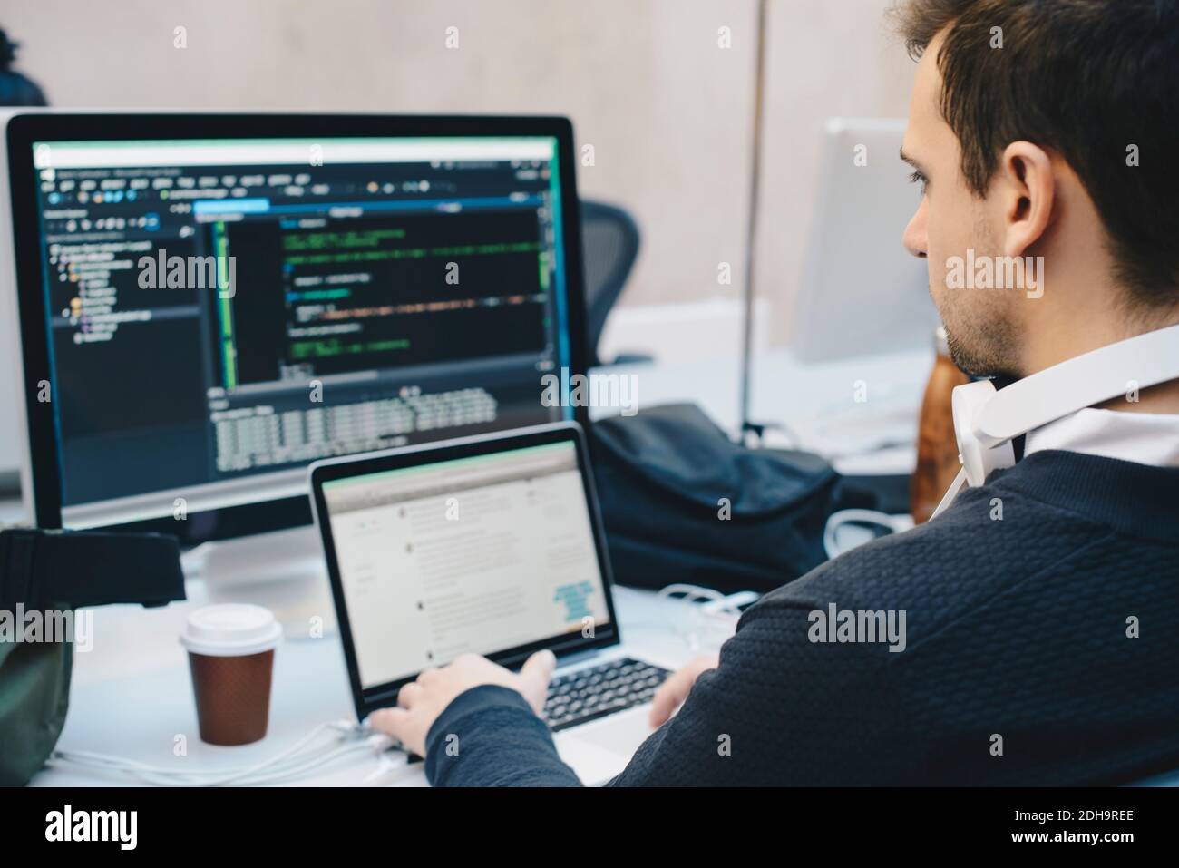 Over the shoulder view of businessman programming on computers at ...