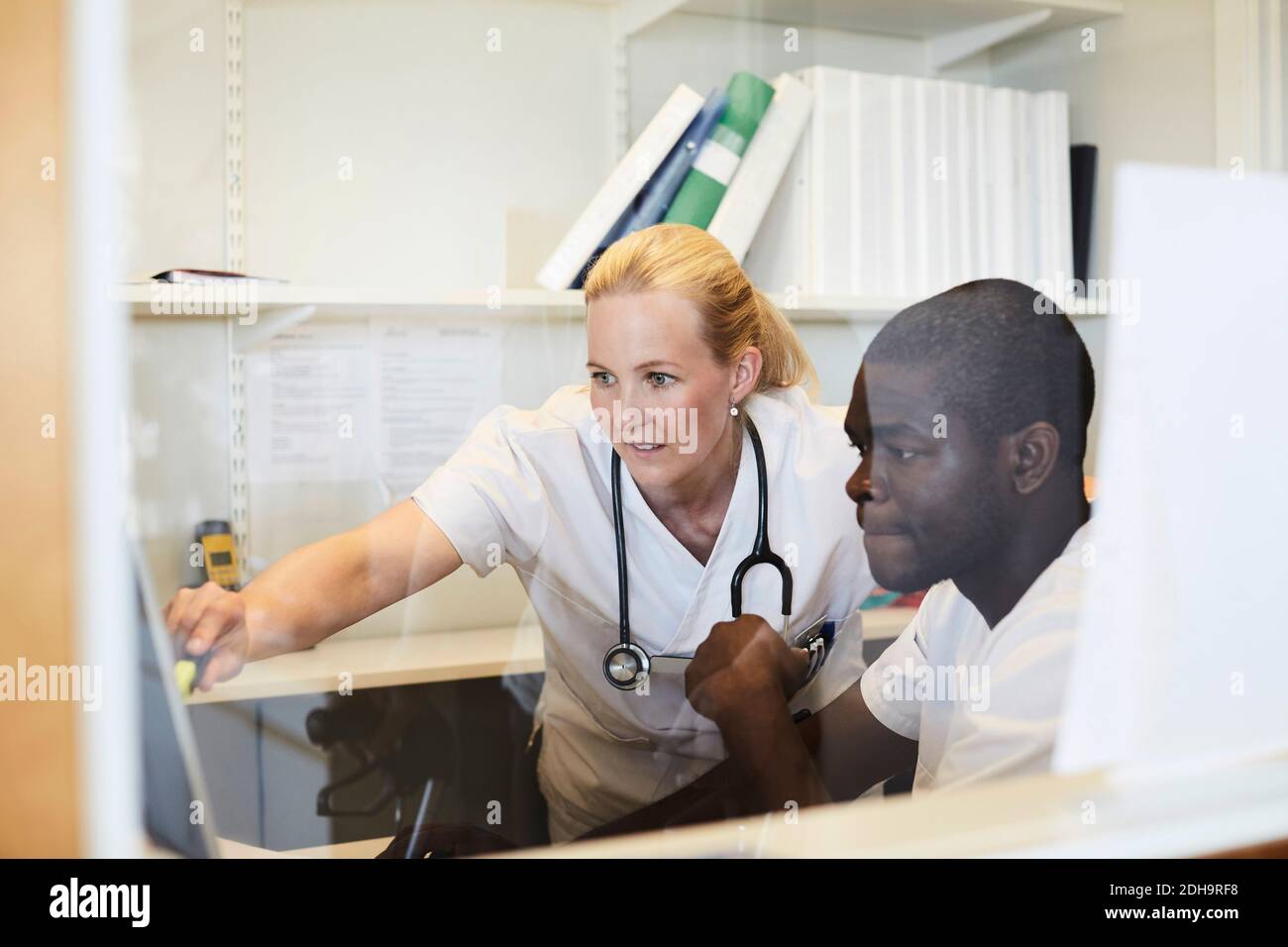 Male and female nurses discussing over desktop computer in hospital ...
