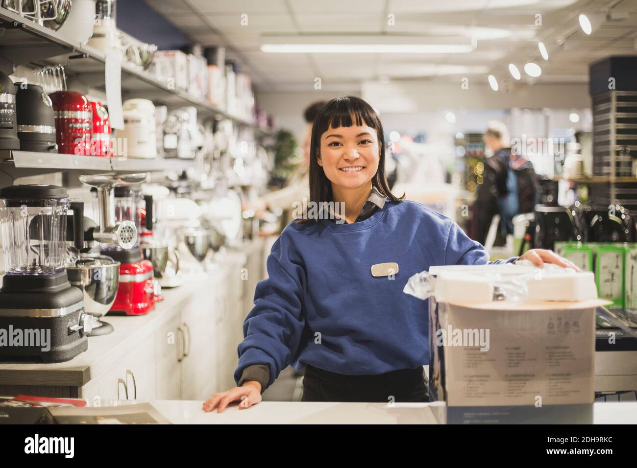 Portrait of smiling saleswoman with appliance standing in store Stock ...