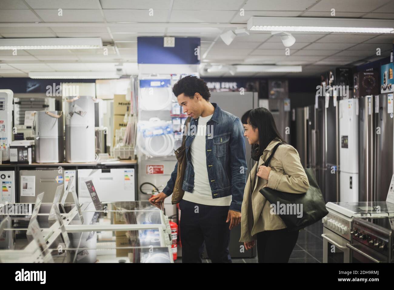 Male and female friends looking at appliances in electronics store ...