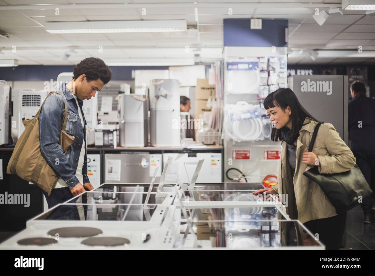Male and female customer looking at appliances in electronics store ...