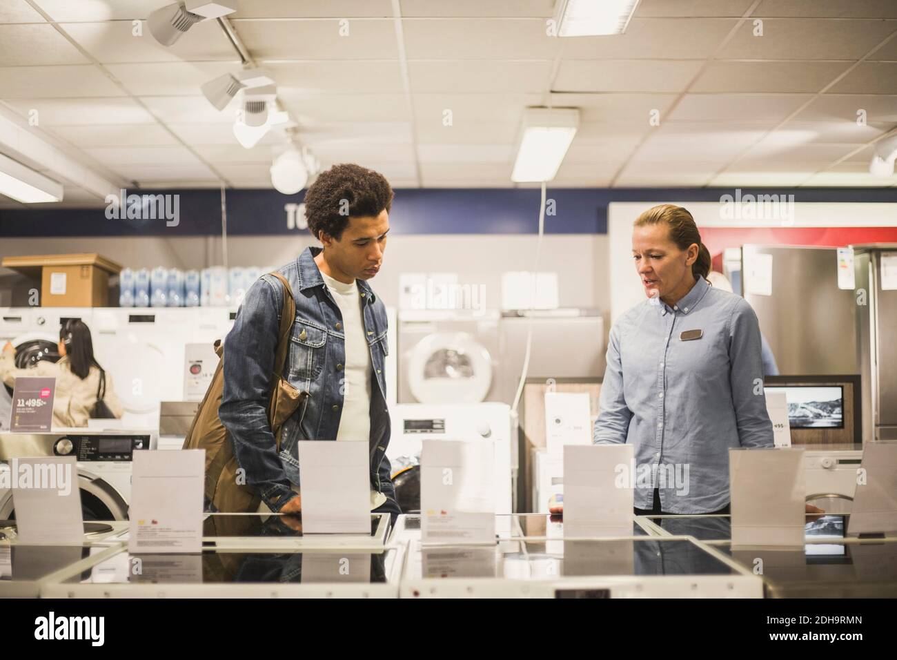 Mature female owner explaining about appliance to young customer while ...