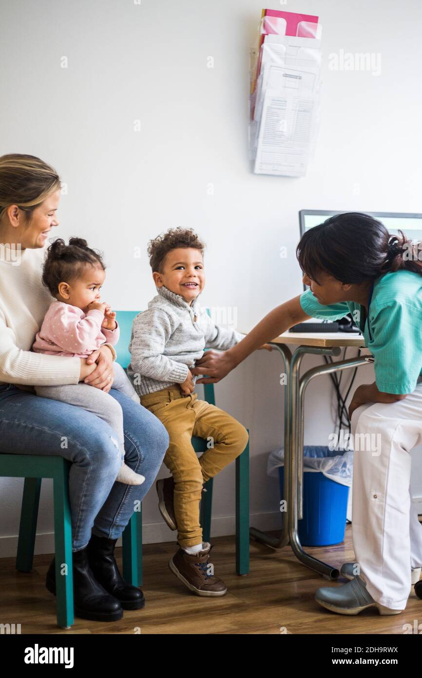 Female doctor examining boy's stomach while mother sitting with ...