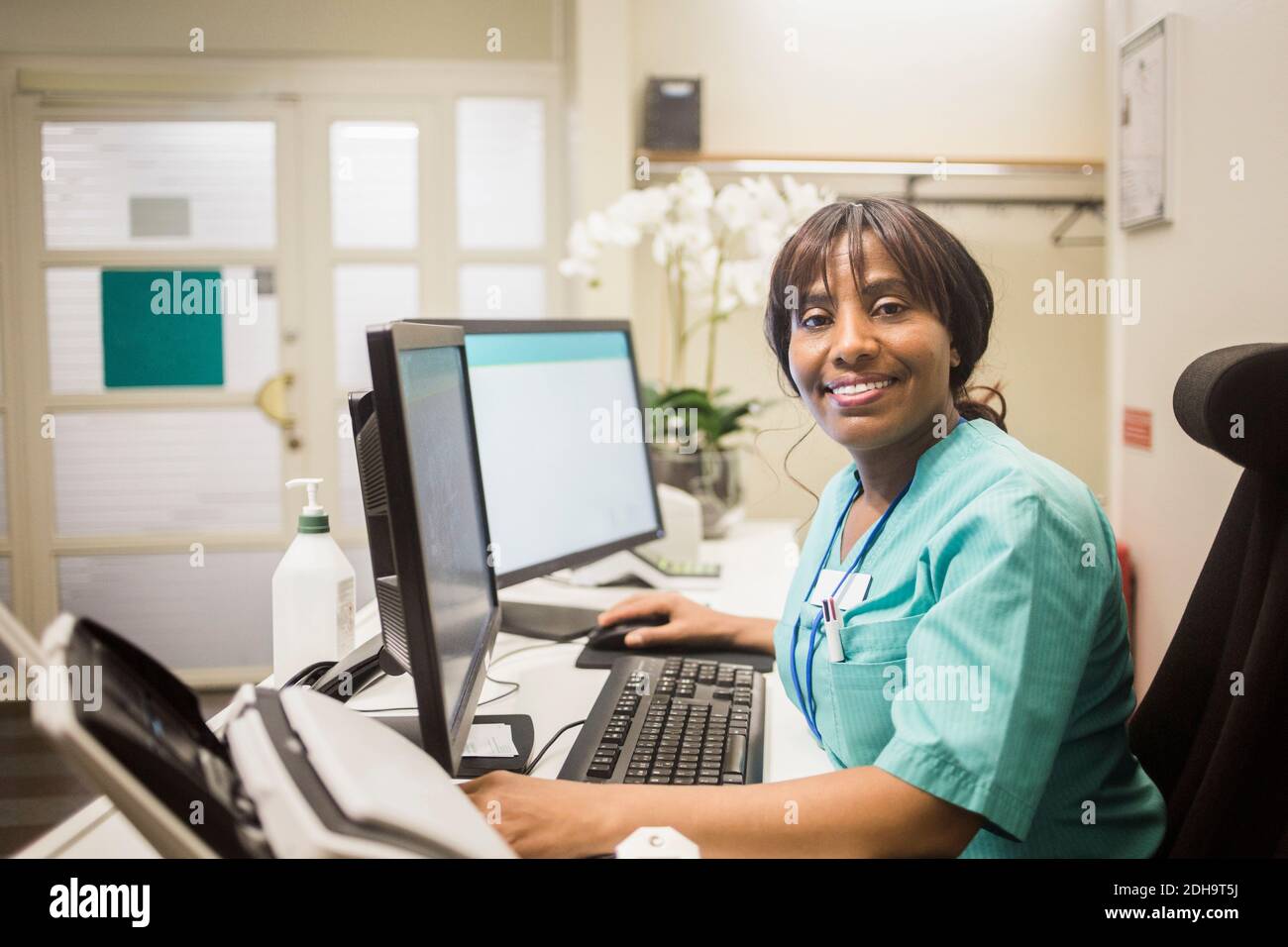 Portrait of mature female doctor with bangs working over computer while ...
