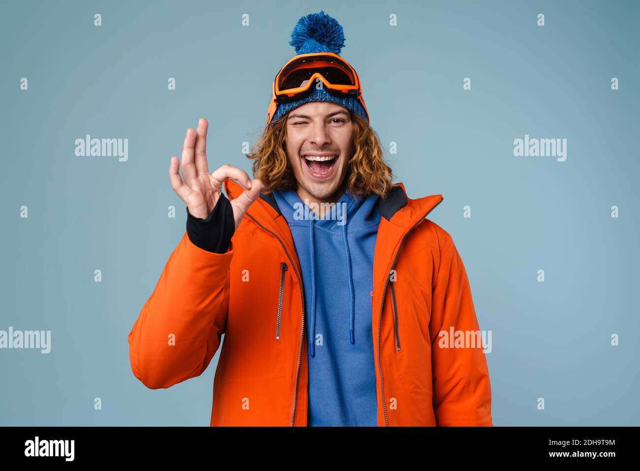 Young excited sportsman winking and showing ok sign on camera isolated ...
