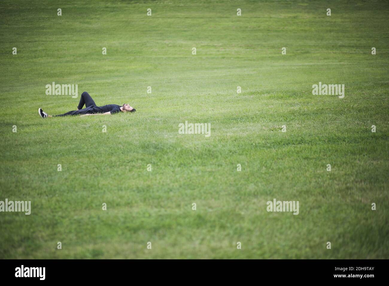 Mid distance view of man lying down over grassy land Stock Photo - Alamy
