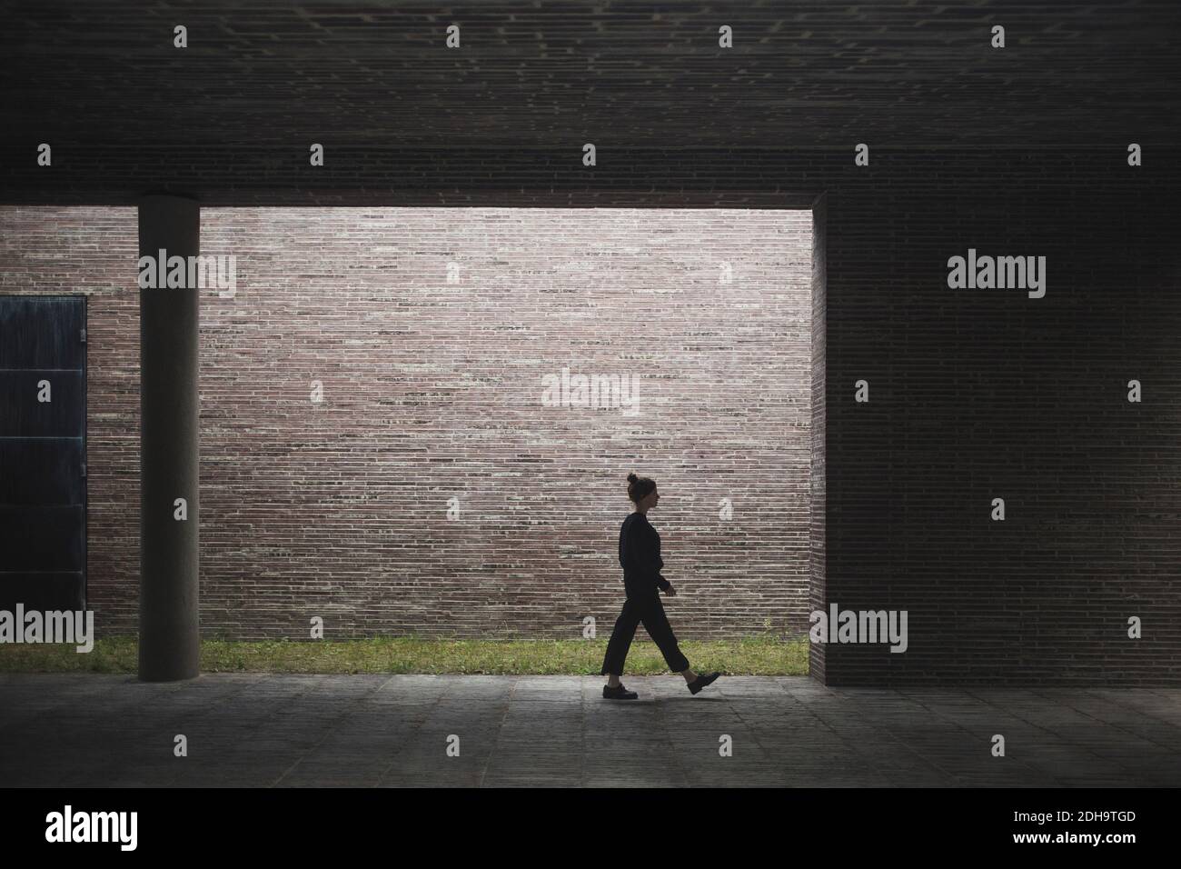 Side view of woman walking against wall Stock Photo - Alamy