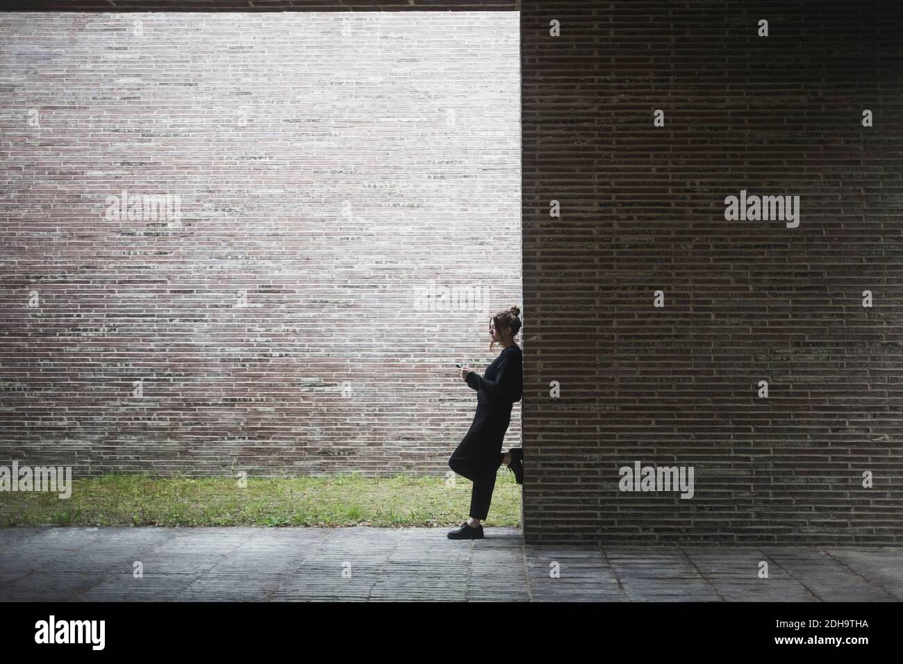 Side view of contemplating woman standing by wall Stock Photo - Alamy