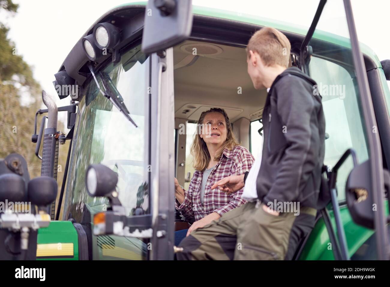 Teenage boy talking with mother in tractor Stock Photo - Alamy