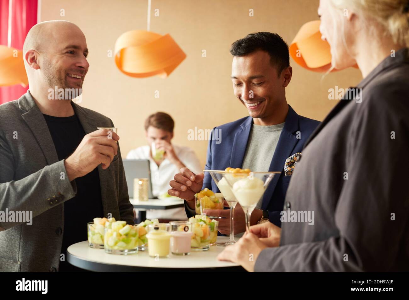 Smiling business people talking while eating food at office seminar ...