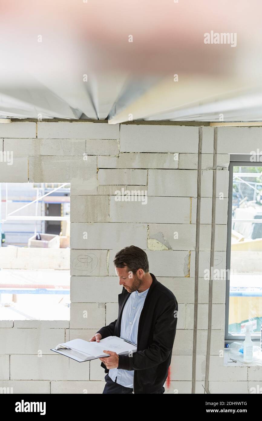 Mature architect reading document at incomplete building Stock Photo ...