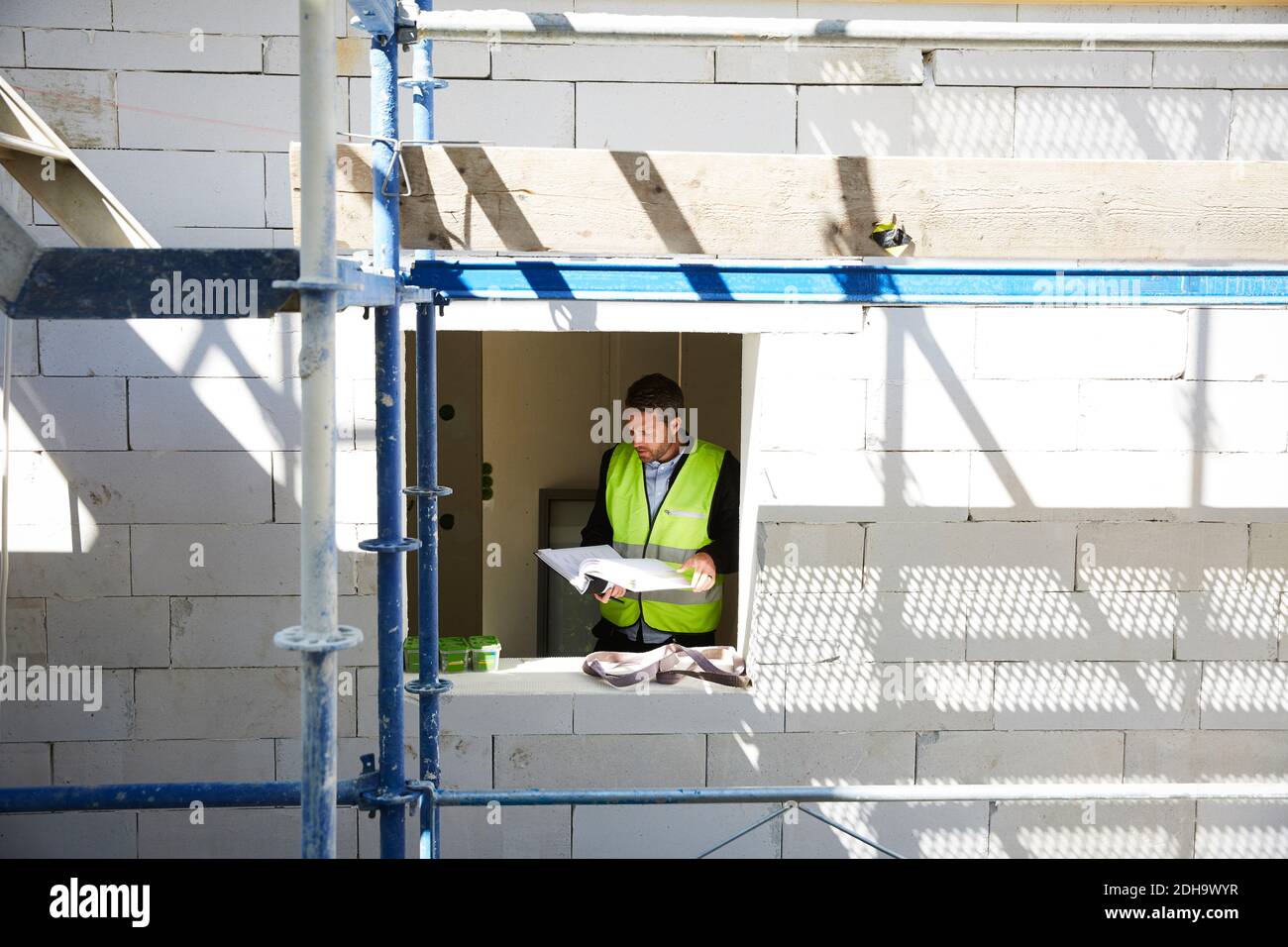 Architect analyzing blueprints while standing at incomplete building ...