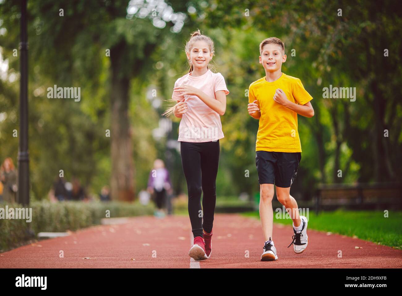 Sports and fitness in adolescence. Caucasian twins boy and girl run on ...