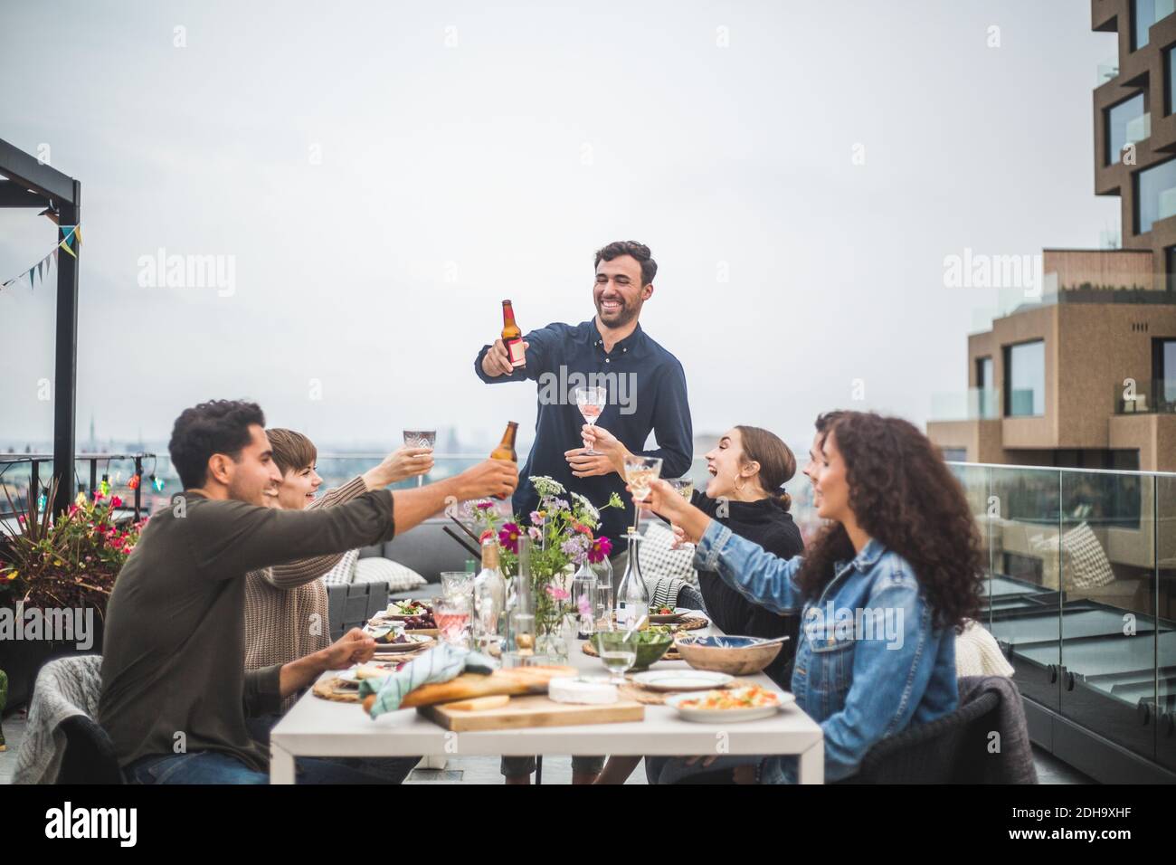 Young male toasting drinks with friends during social gathering on ...