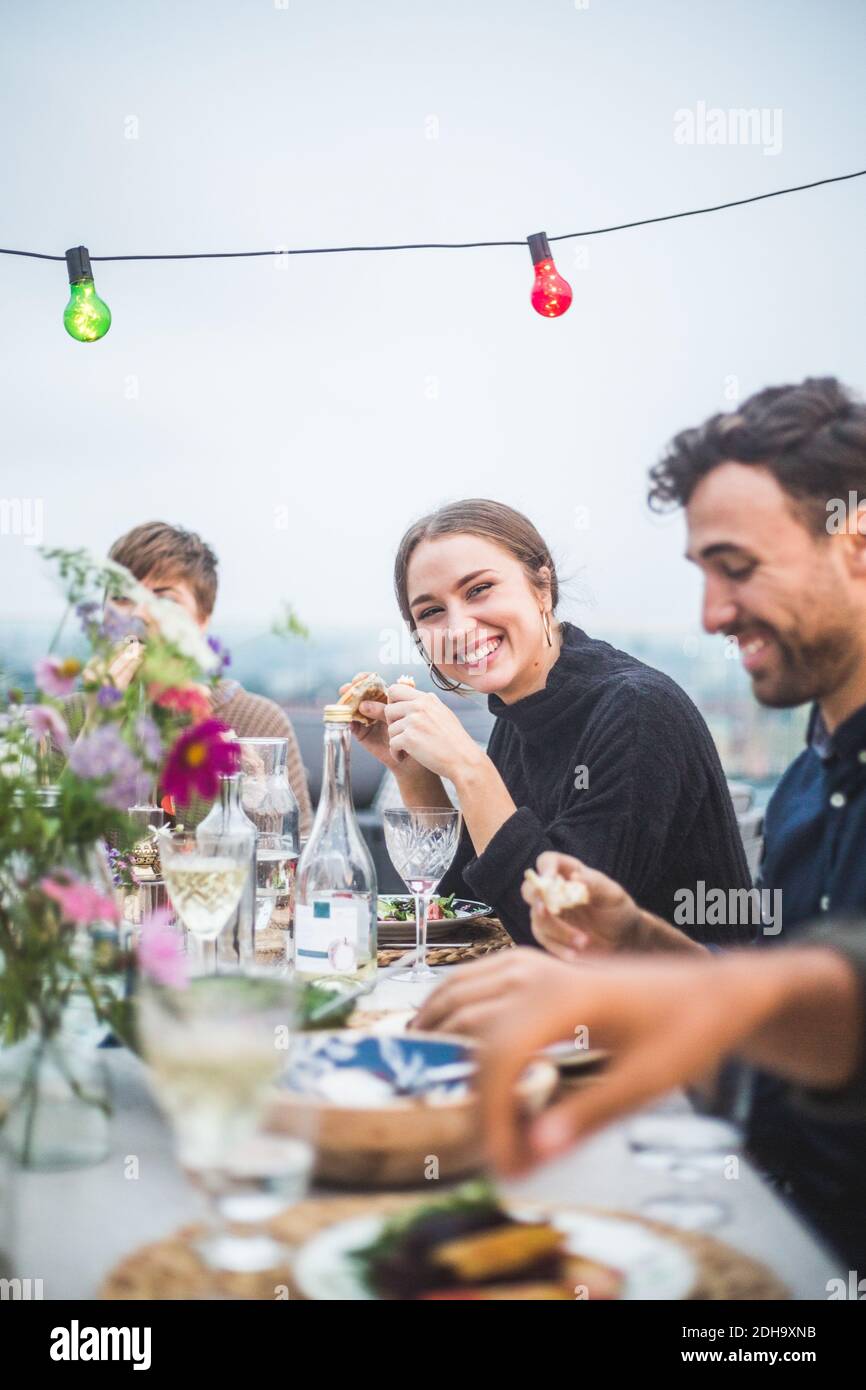 Portrait of smiling female sitting with friends during social gathering ...