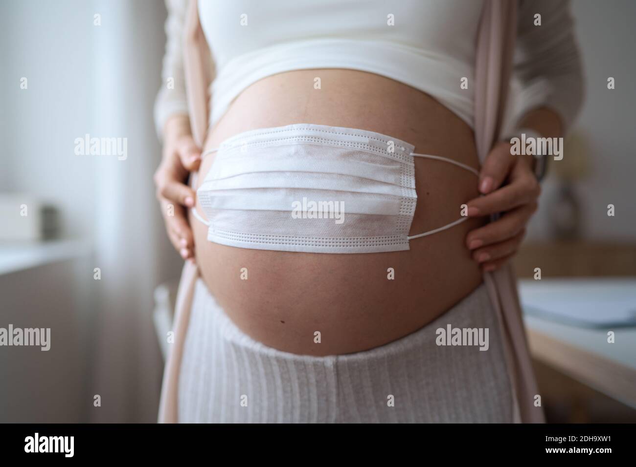 Pregnant mother use face mask covering on her abdomen for protecting ...