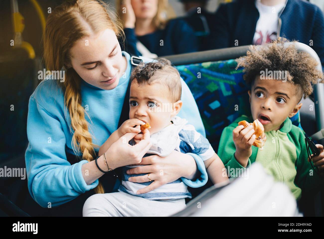 Mother feeding baby boy while sitting with son in bus Stock Photo - Alamy
