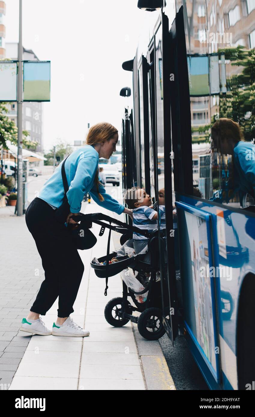 Mother boarding bus with baby stroller at city Stock Photo - Alamy