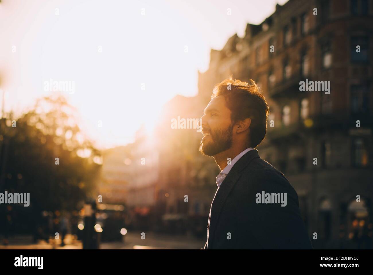 Side view of smiling man standing against sky in city Stock Photo - Alamy