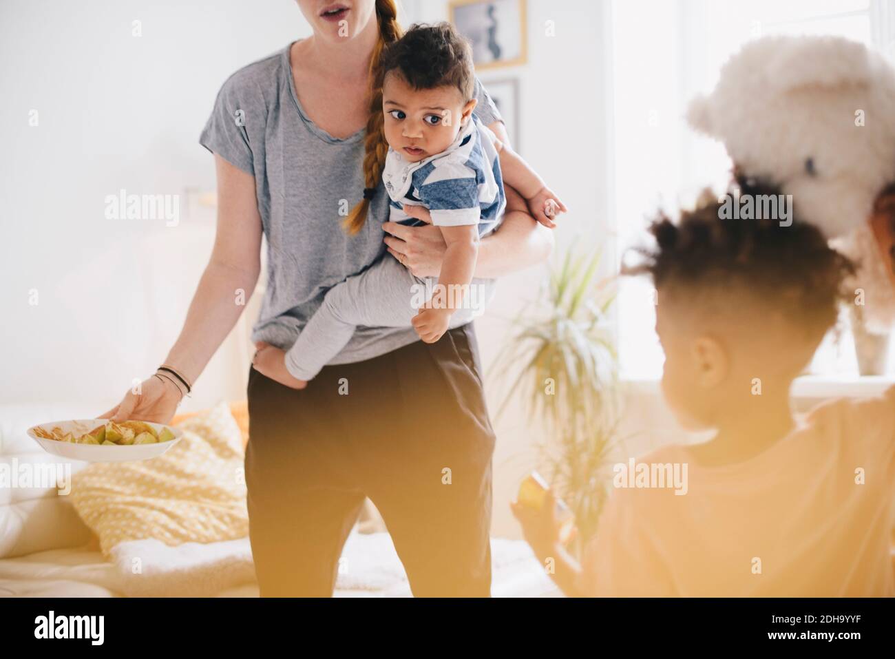Midsection of mother carrying plate and son while standing by boy at ...