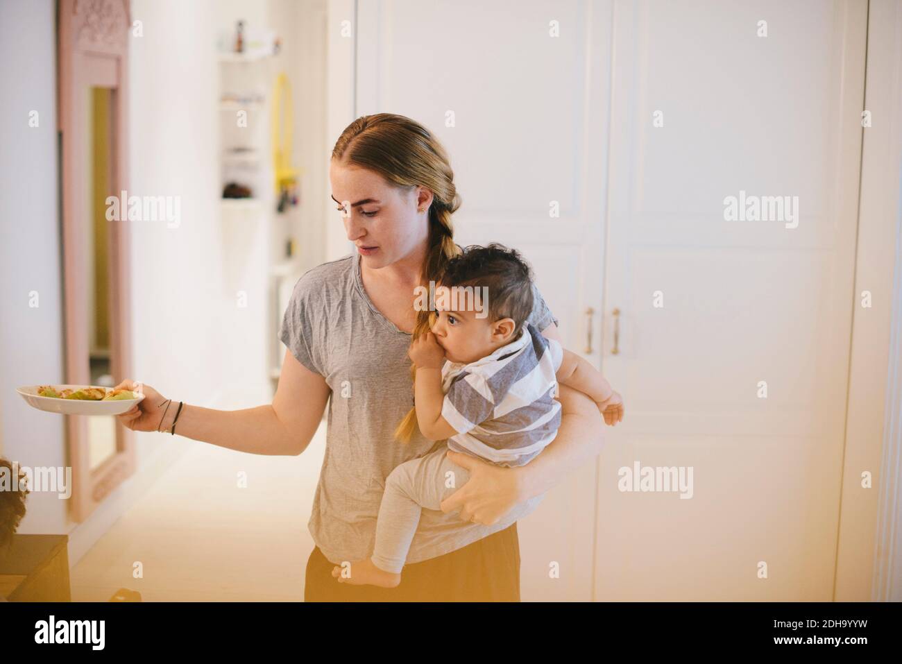 Mother carrying son while holding plate at home Stock Photo - Alamy