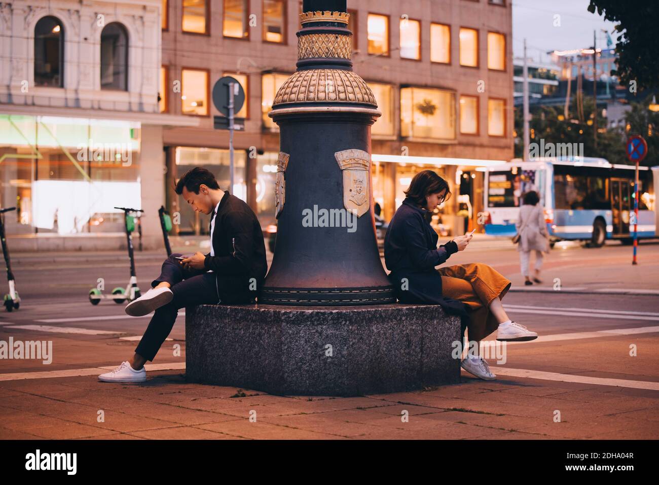 Side view of male and female surfing net while sitting in city during ...