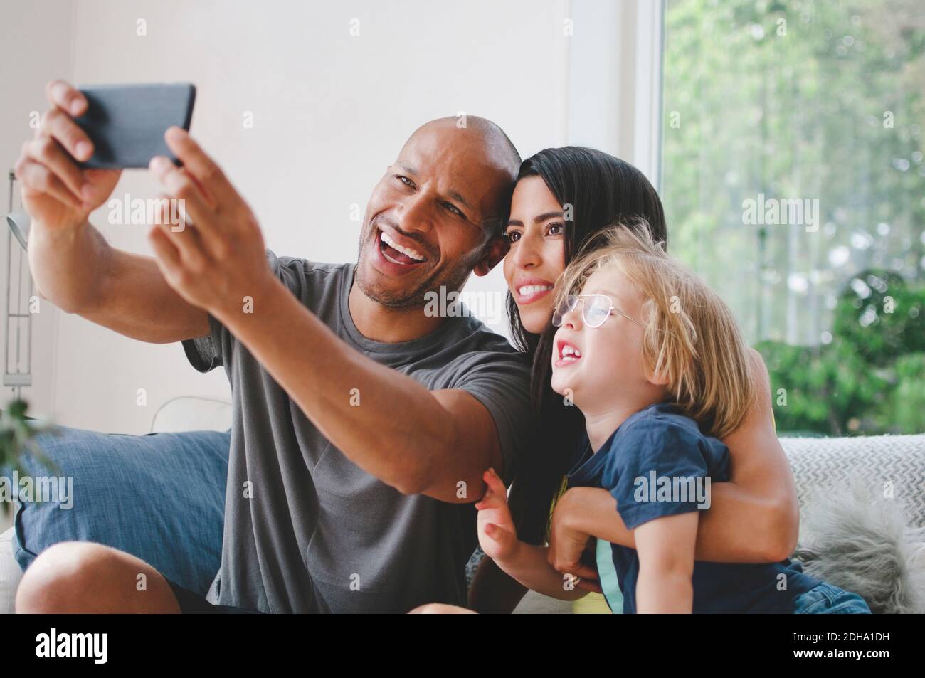Happy parents taking selfie with son through smart phone on sofa at ...