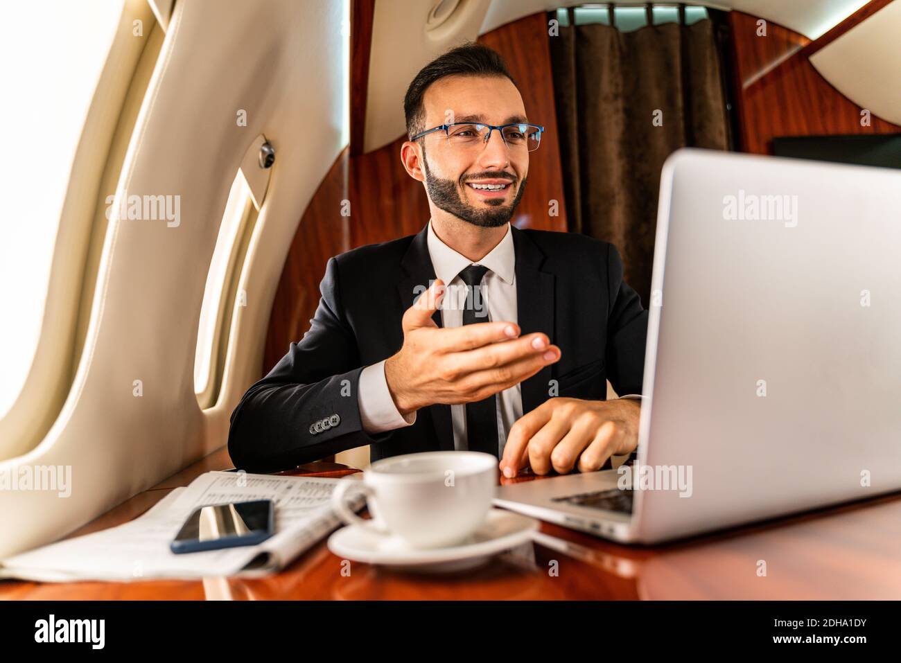 Handsome businessman wearing elegant suit flying on exclusive private ...