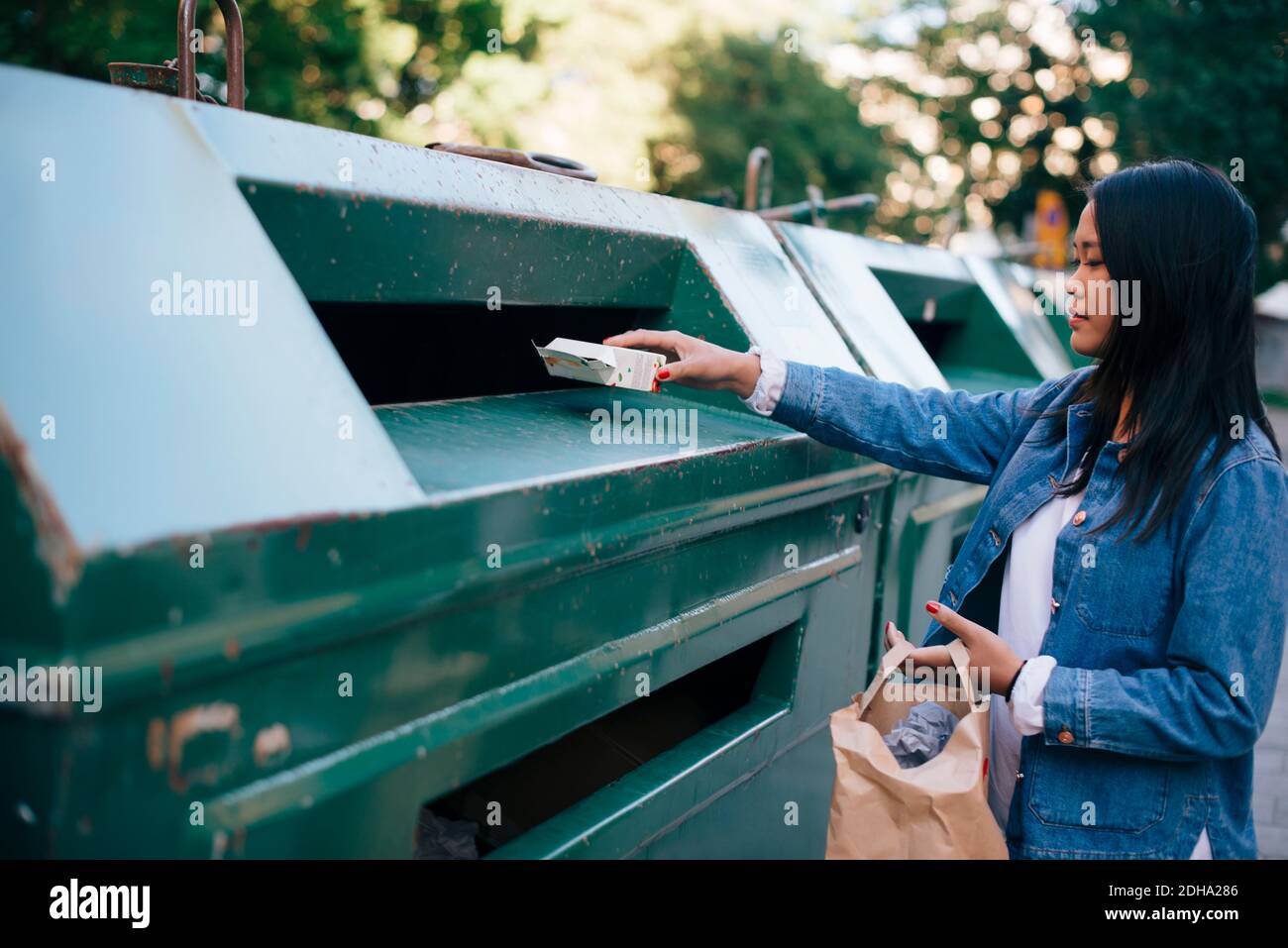 Teenage girl throwing packet in garbage can Stock Photo - Alamy