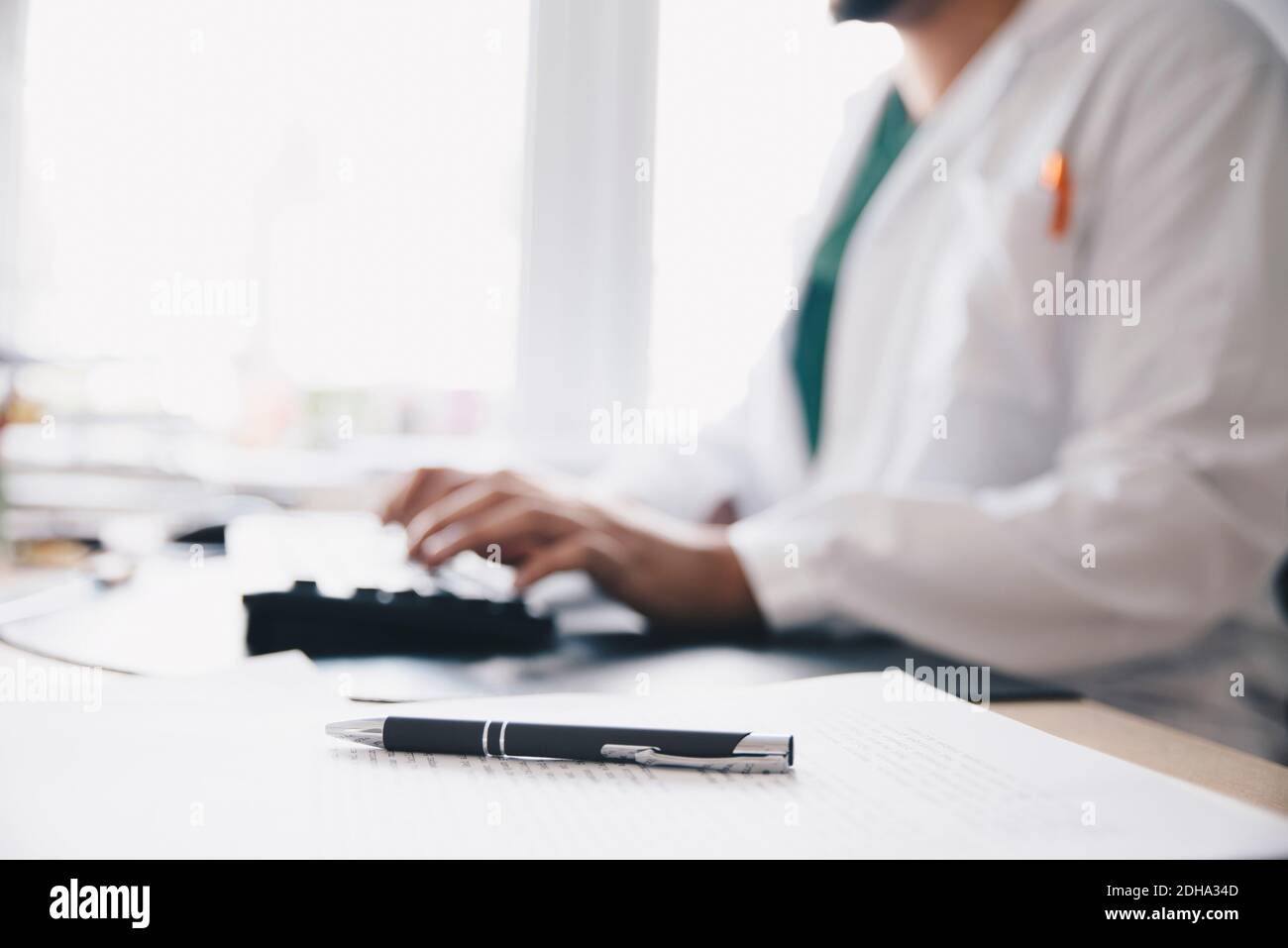 Midsection of male doctor typing on keyboard at office in hospital ...