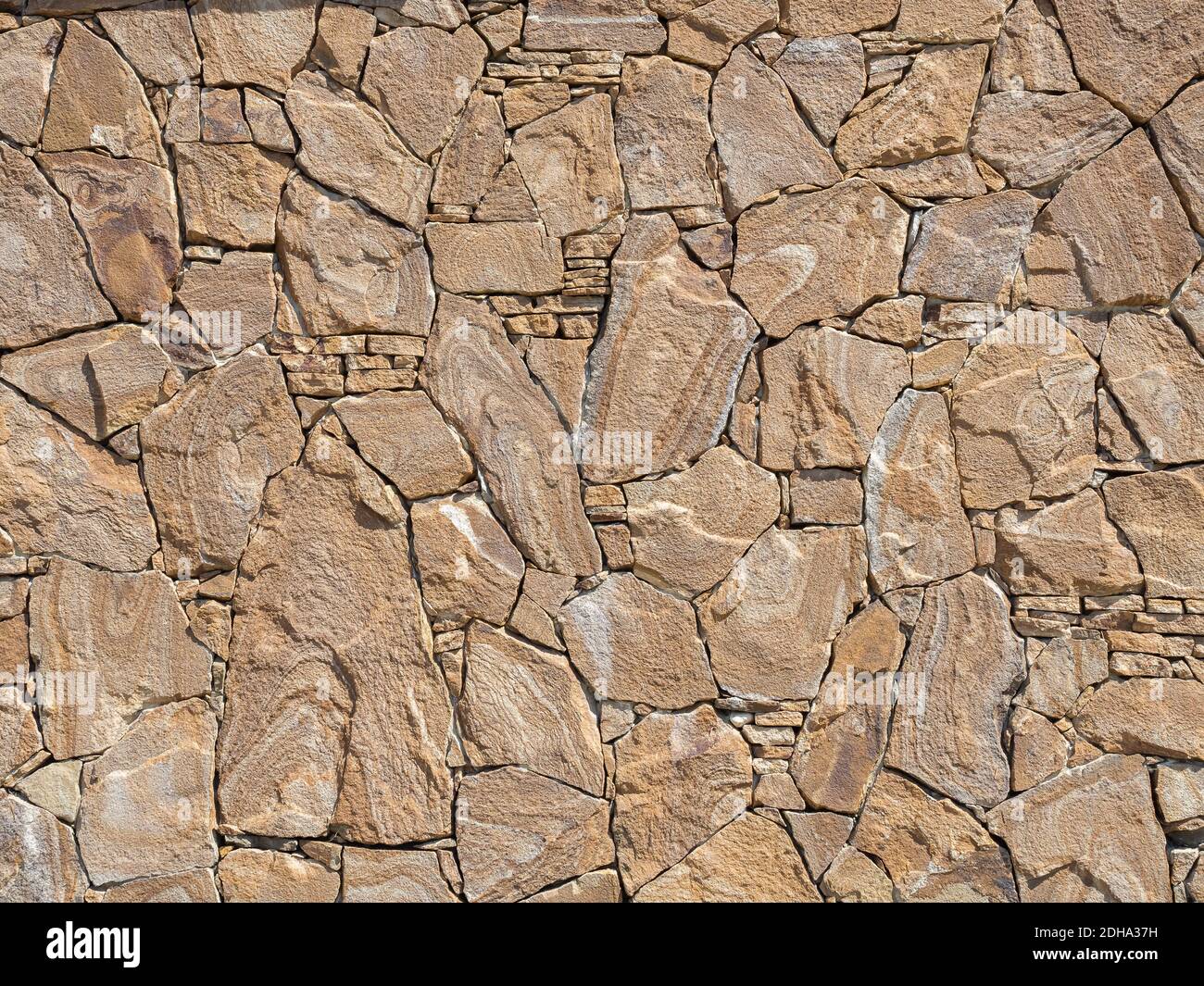 A decorative wall made of rough stones of various shapes and sizes ...