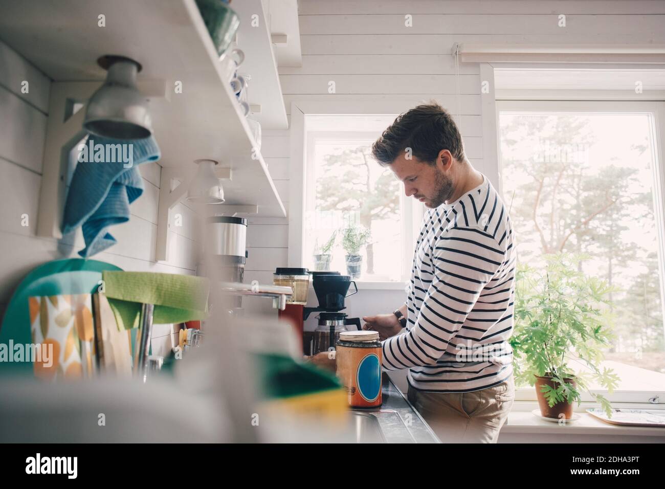 Side view of man making coffee in kitchen at home Stock Photo - Alamy