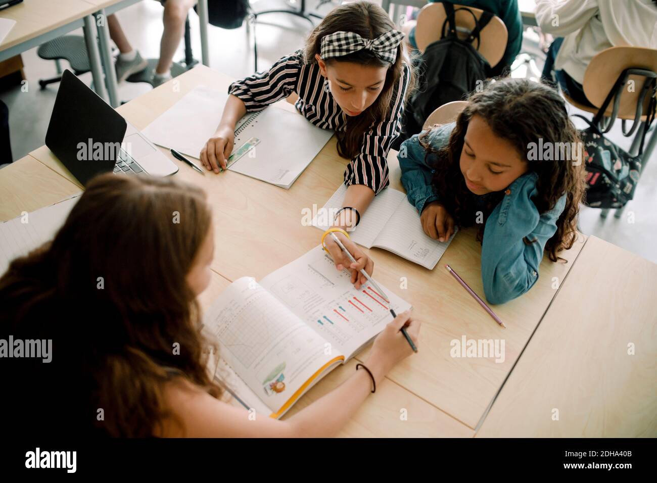 High angle view of female students studying from book in classroom ...