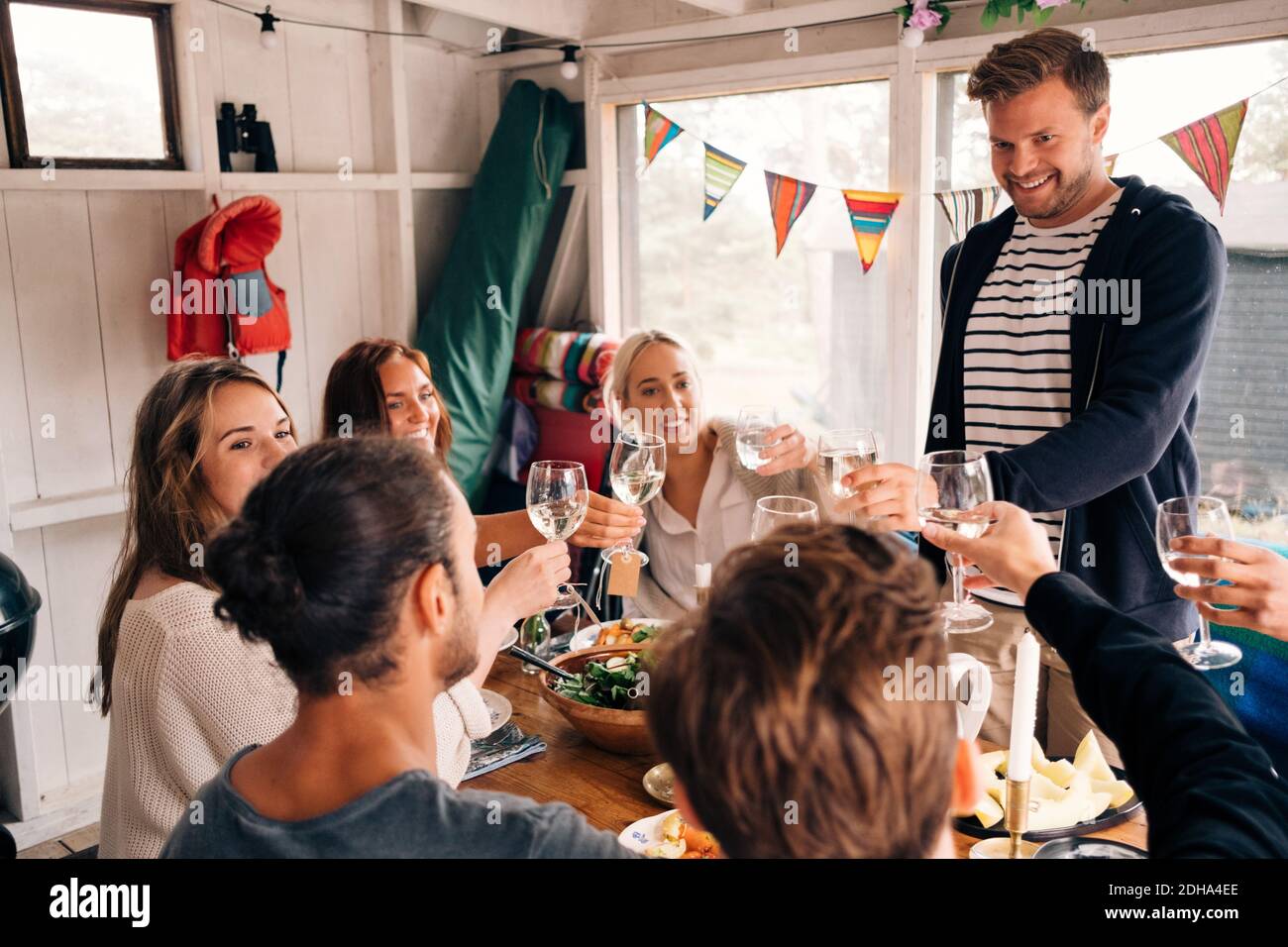 Happy young man toasting wineglass with friends during lunch party ...