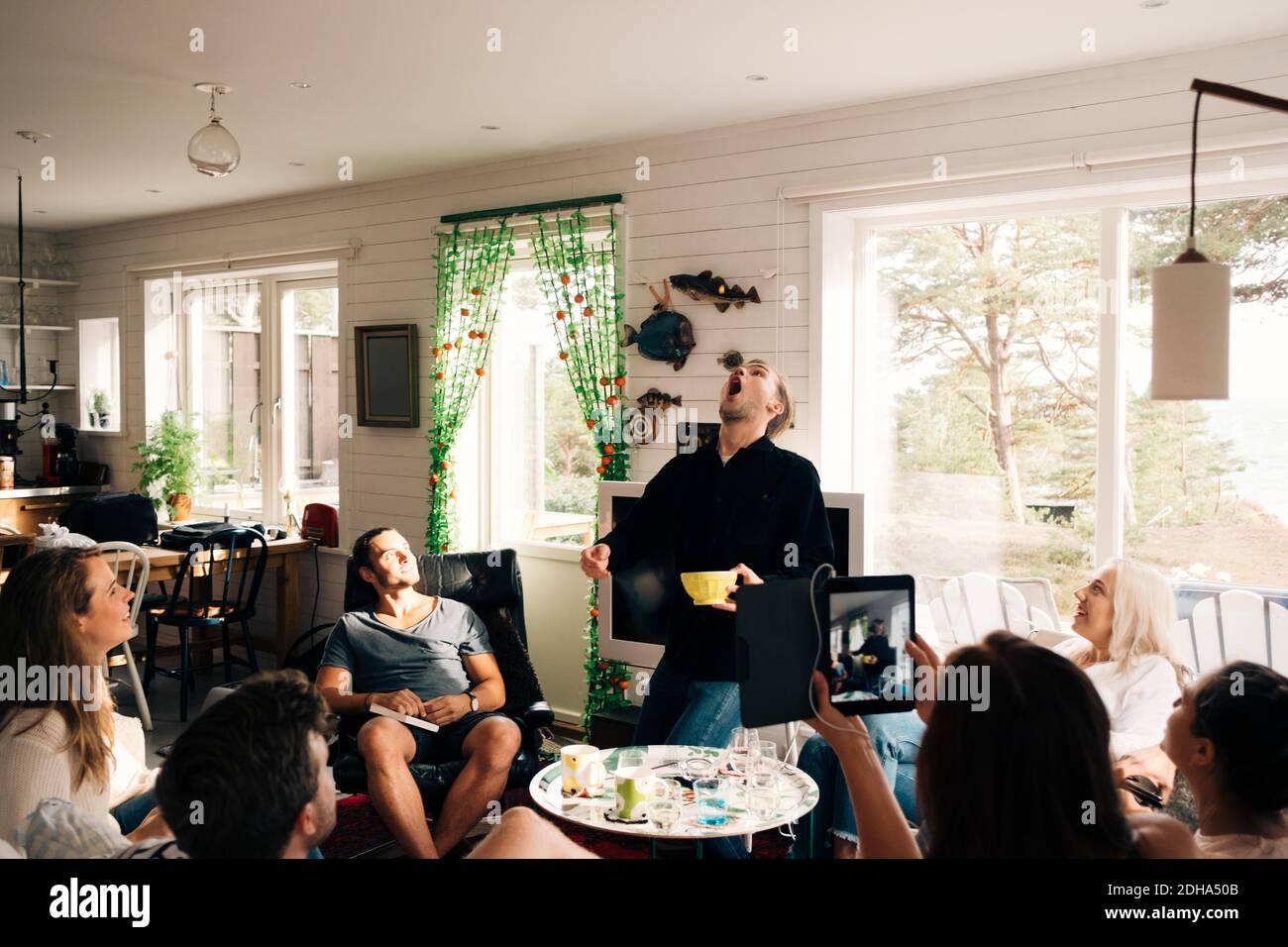 Playful young man catching snack with mouth while friends watching him ...