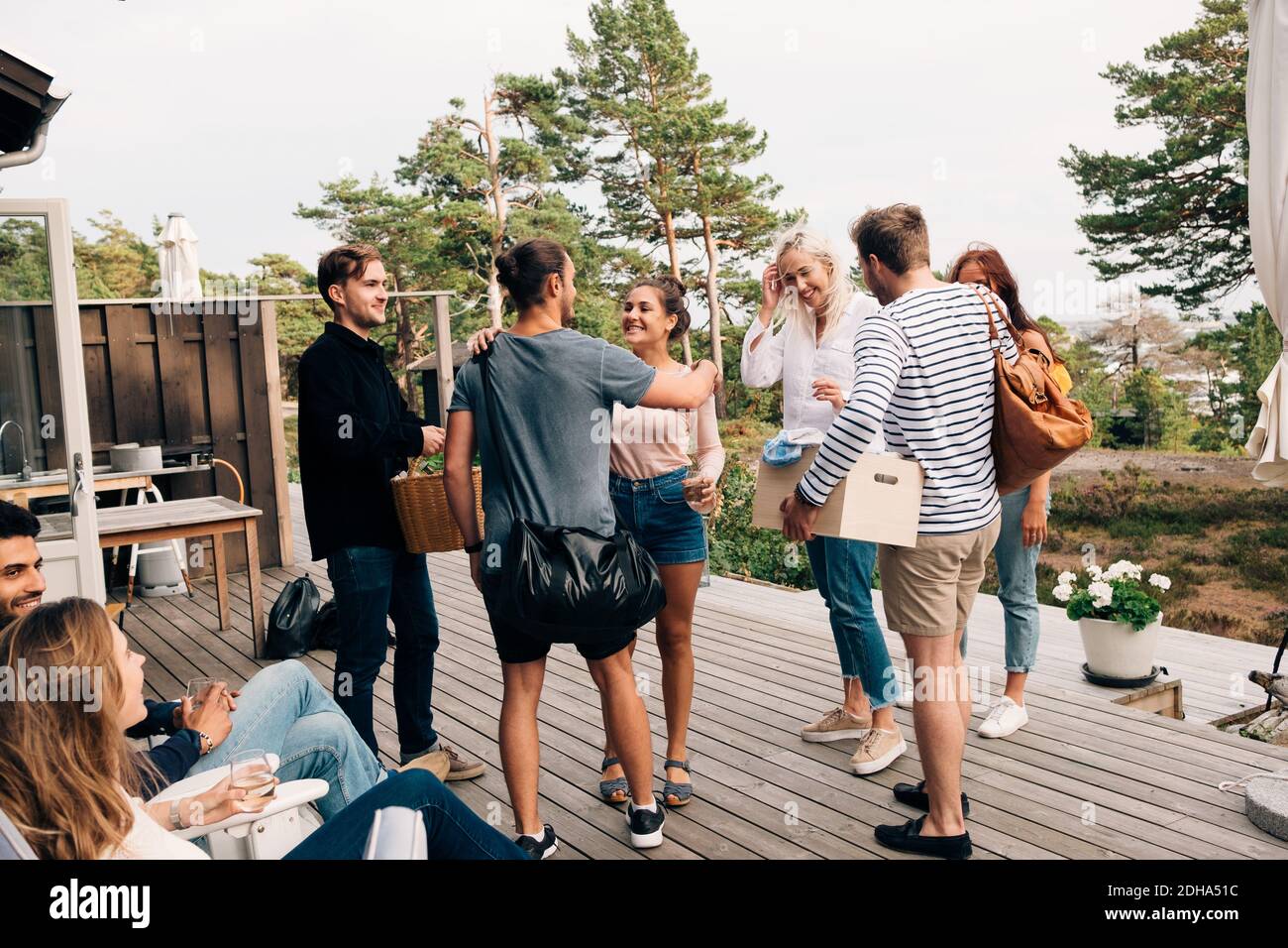 Happy friends greeting each other on cottage deck Stock Photo - Alamy