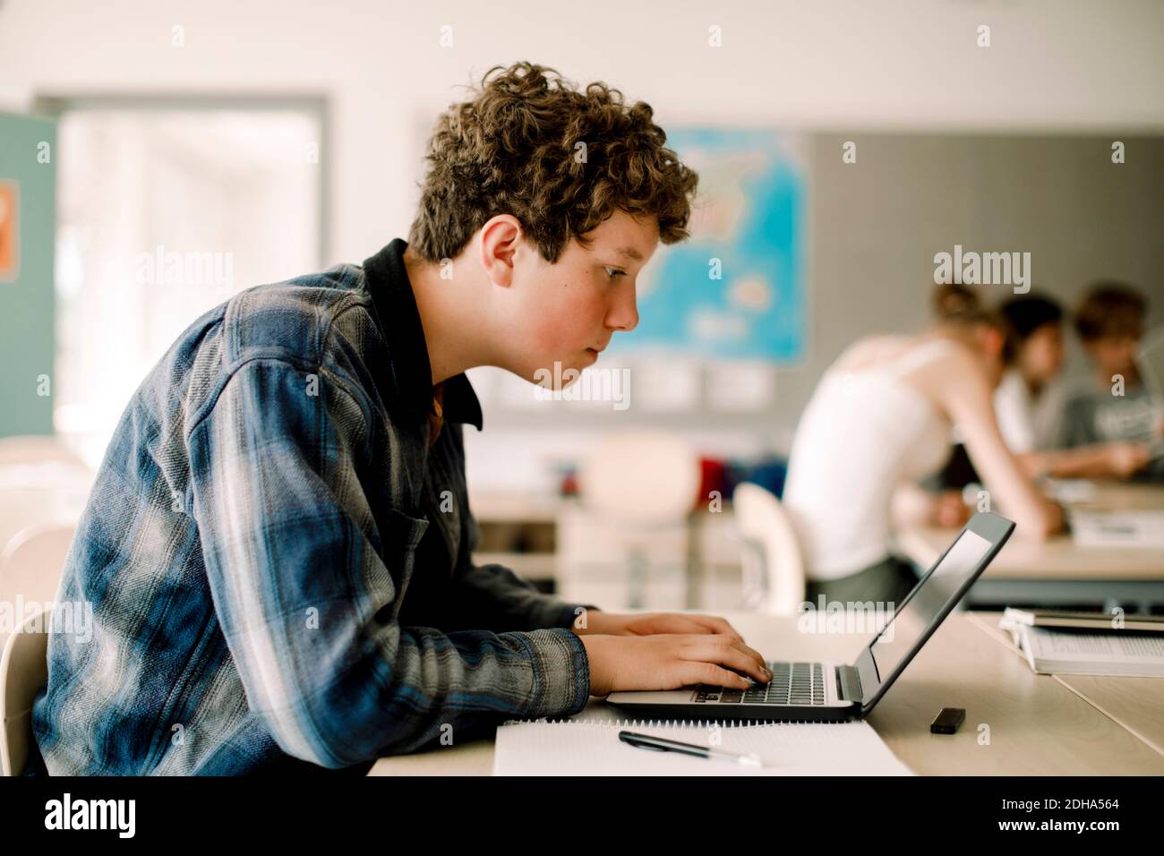 Side view of teenage boy using laptop while sitting in classroom Stock ...