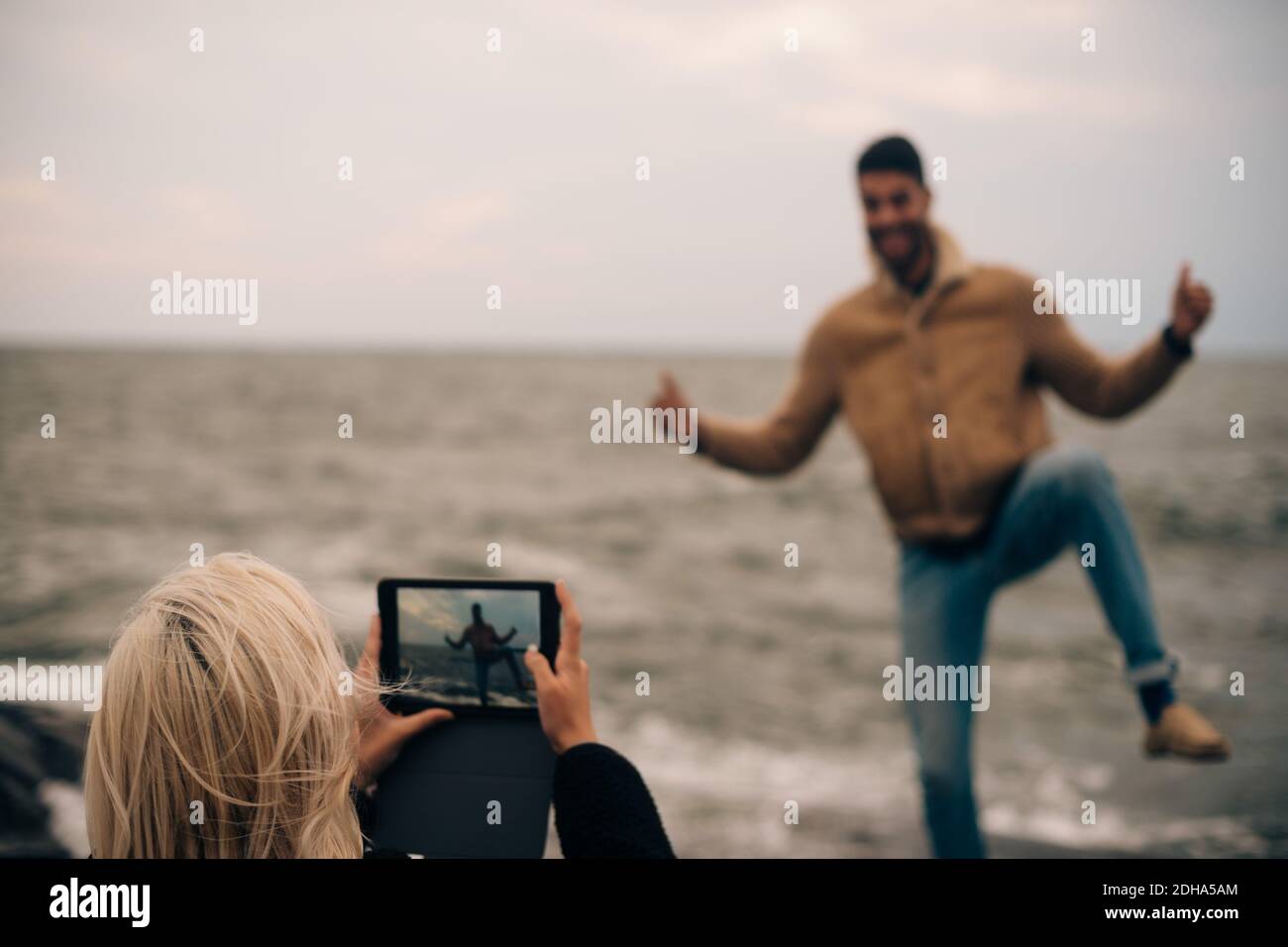Young woman photographing man on digital tablet at beach Stock Photo ...