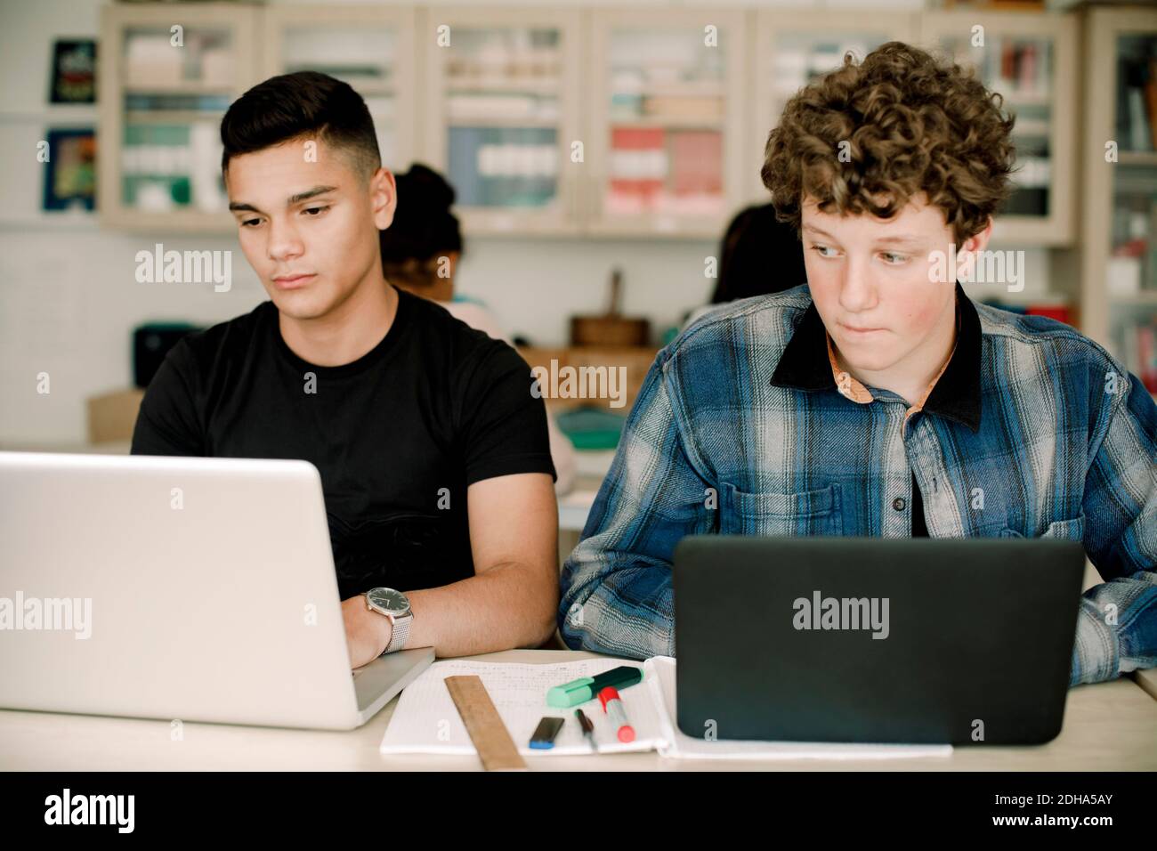 Male students using laptop over table while sitting in classroom Stock ...
